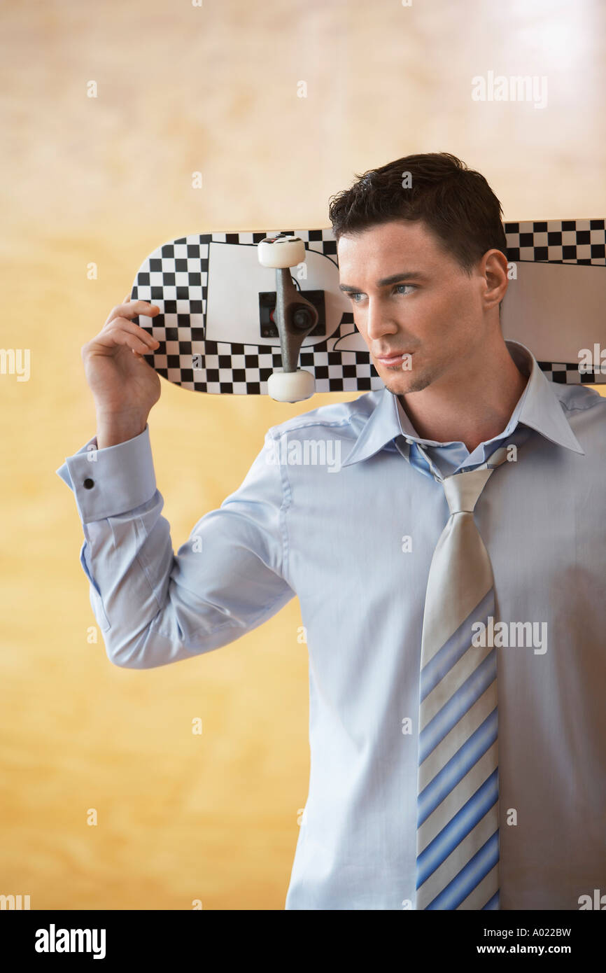 Man holding skateboard behind head, portrait Stock Photo - Alamy
