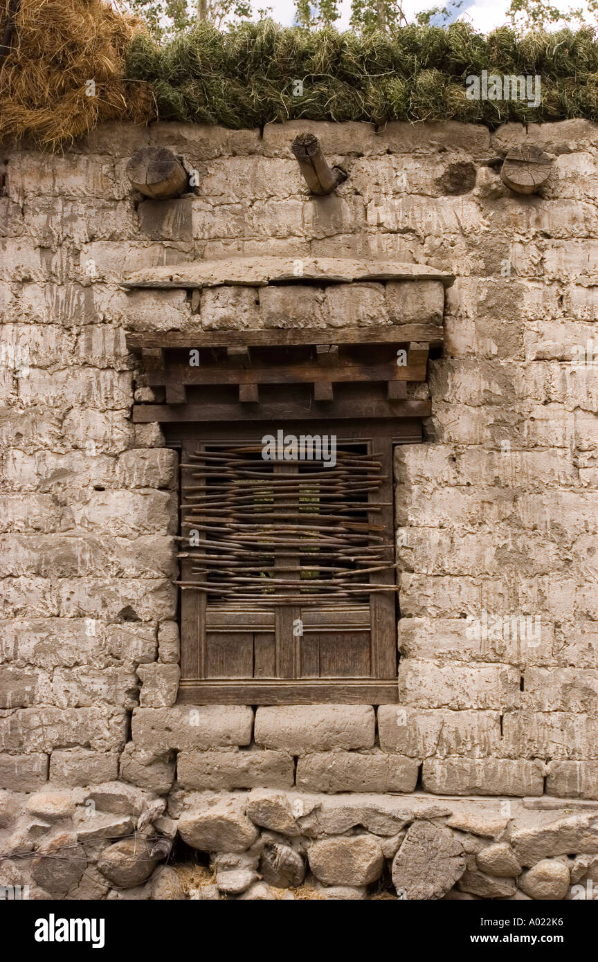 Ladakhi building facade with wooden window and grass drying on the roof ...