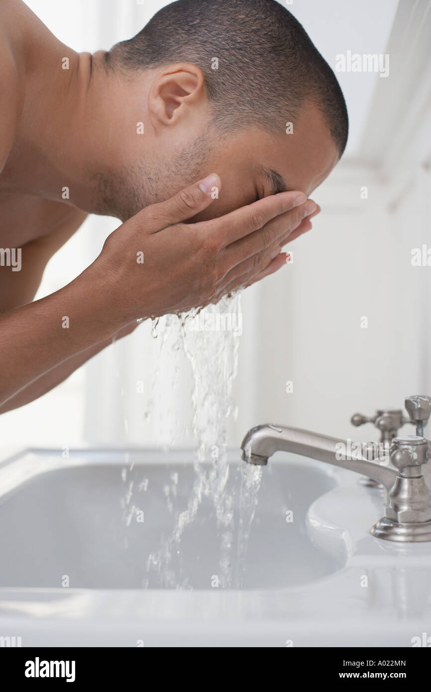 Man washing face in bathroom sink Stock Photo - Alamy