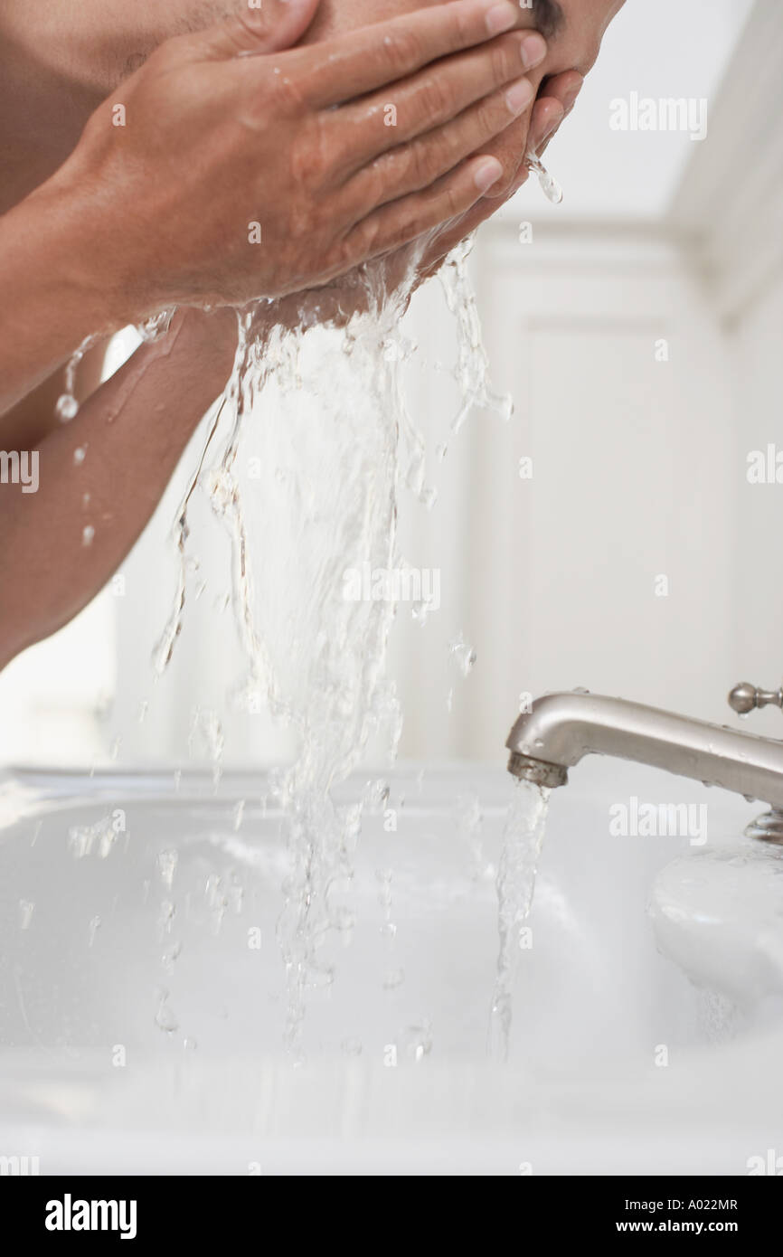 Man washing face in bathroom sink Stock Photo - Alamy
