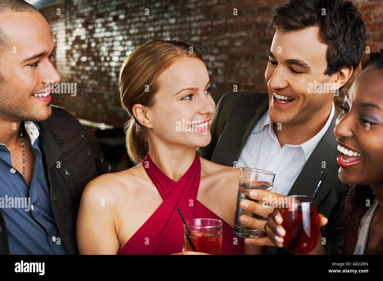 Two couples laughing, holding drinks in bar Stock Photo - Alamy