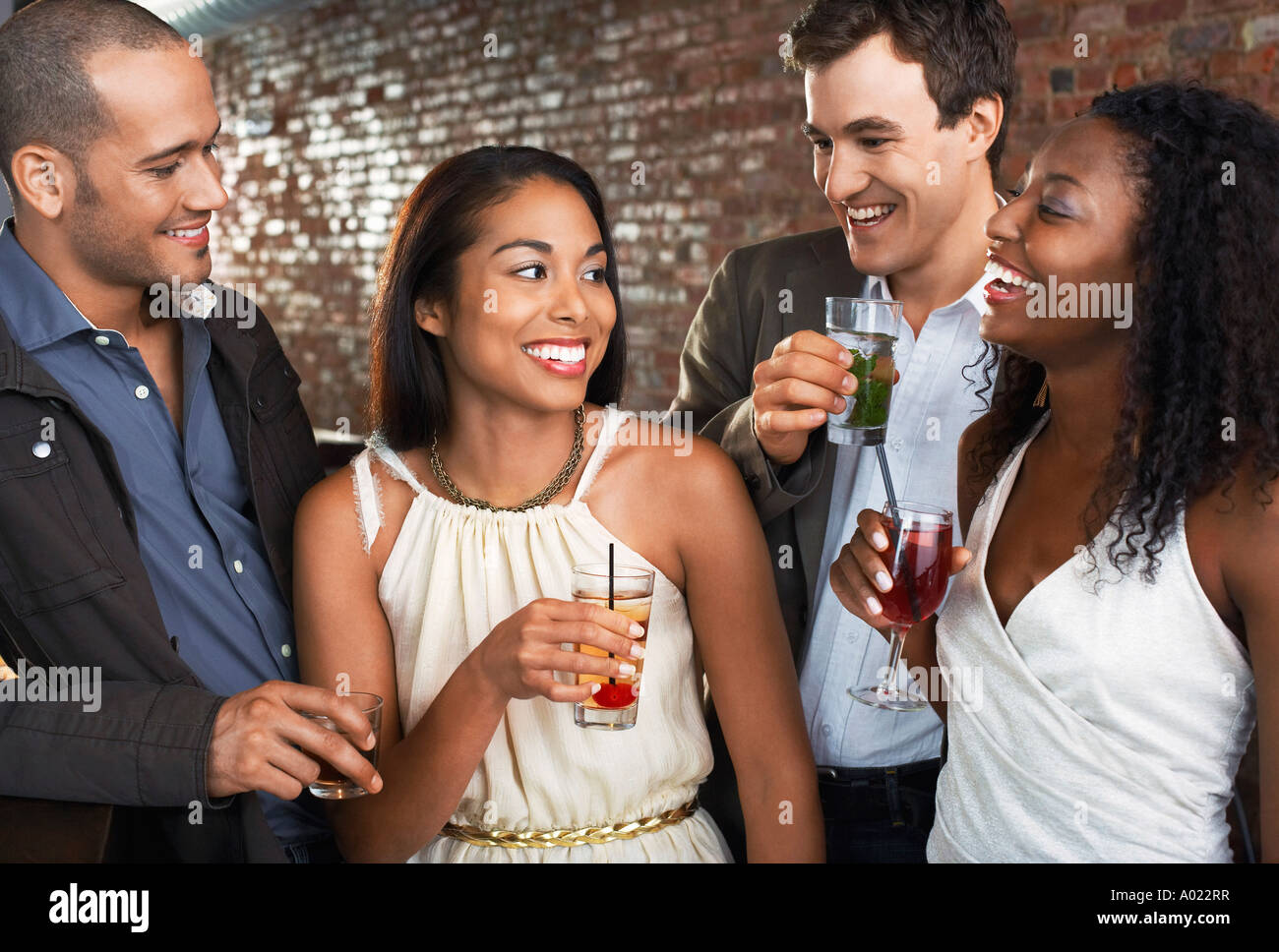Two couples holding drinks, standing in bar Stock Photo - Alamy