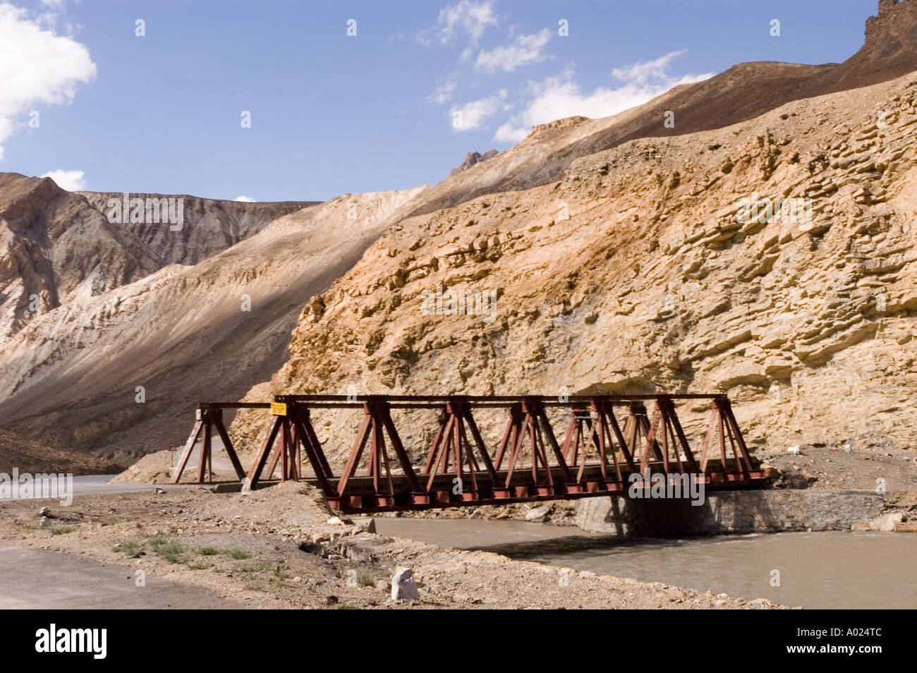 Red metal truss bridge over a river on the Manali Leh strategic road in ...