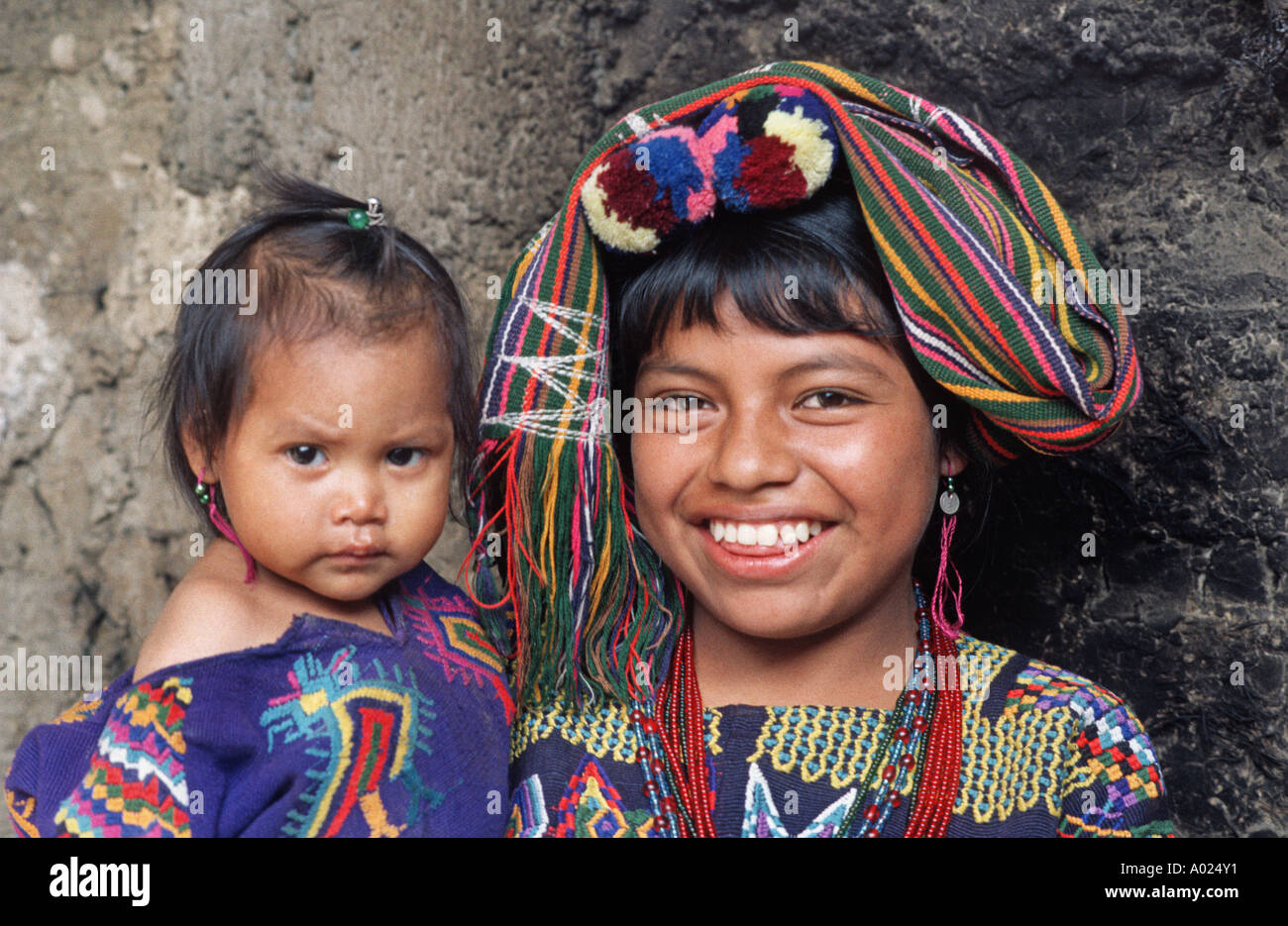 Young Maya woman wearing the brocaded costume of her community holding ...