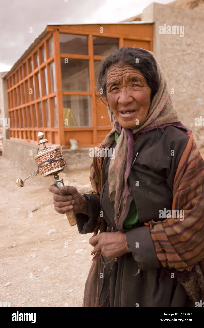 Old Ladakhi woman spinning buddhist prayer wheel and looking in camera ...