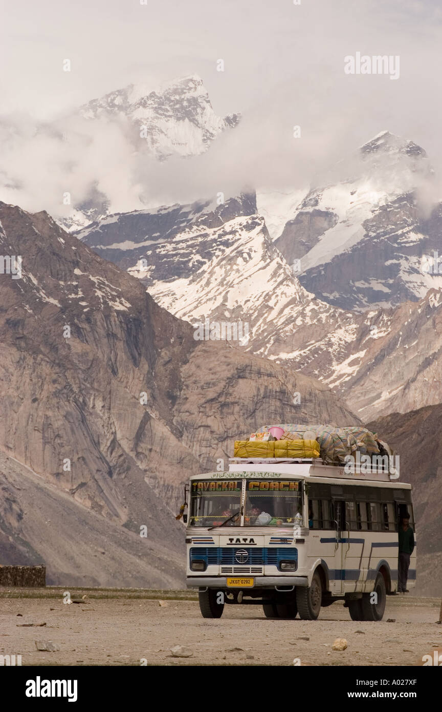 Indian Tata bus with full roof load and snow capped himalayan mountains ...