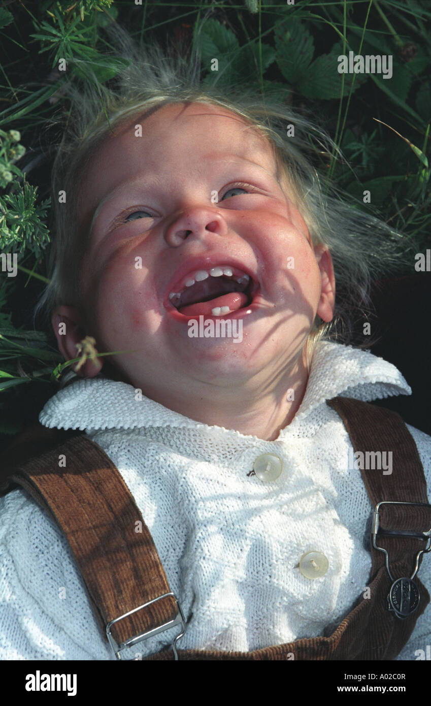 Baby lying on the grass and laughing. Altai. Siberia. Russia Stock ...