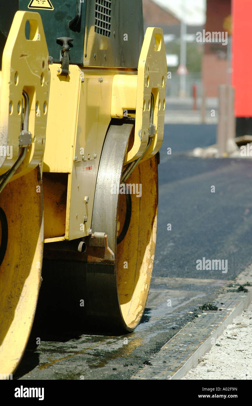 Roller rolling macadam tarmac to make a level surface for a car park ...
