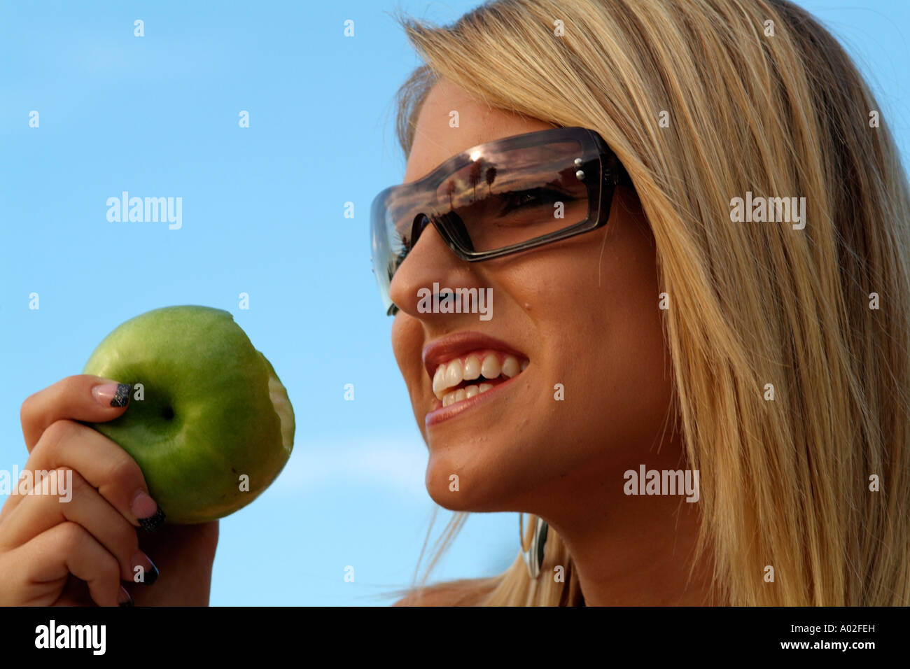 Head shot of an attractive girl eating a green apple Healthy eating ...