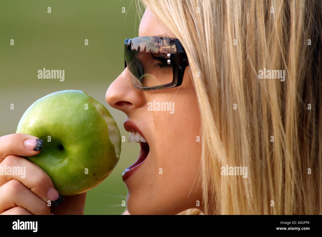 Head shot of an attractive girl eating a green apple Healthy eating ...