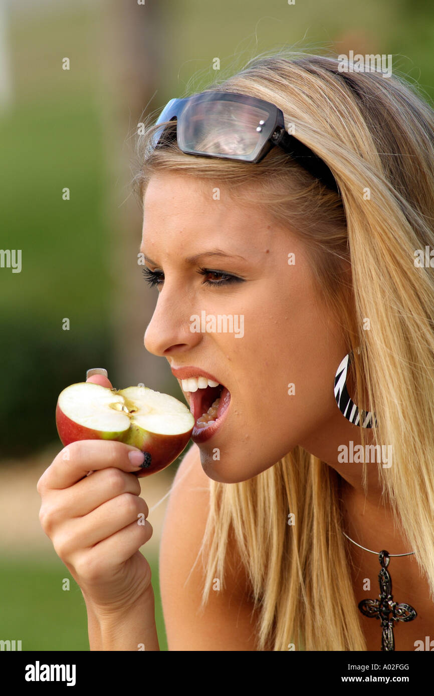 Head shot of an attractive girl eating a red and green apple Healthy ...