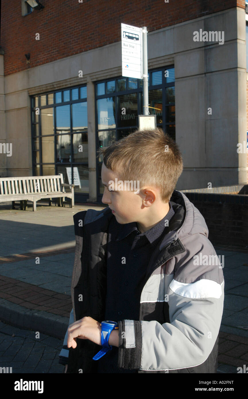 boy checking his watch waiting at bus stop in the uk Stock Photo - Alamy
