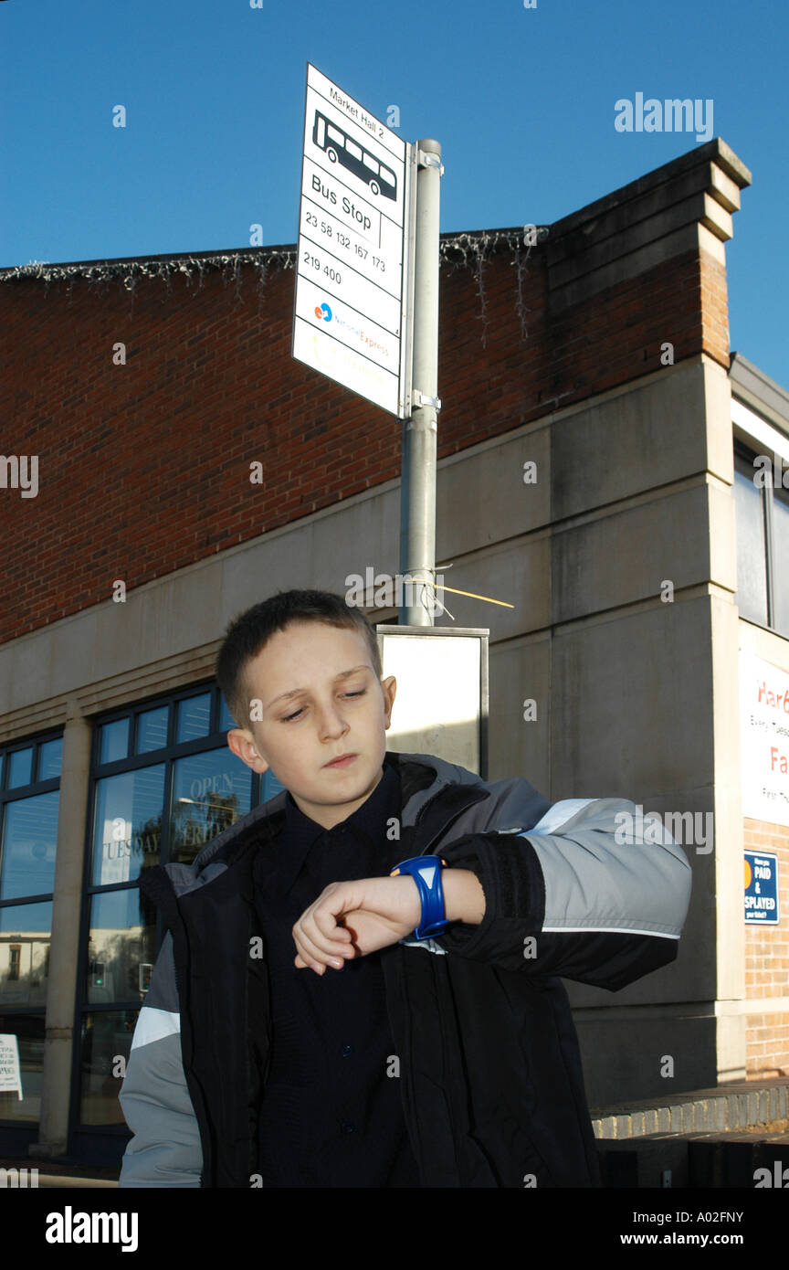 boy checking his watch waiting at bus stop in the uk Stock Photo - Alamy