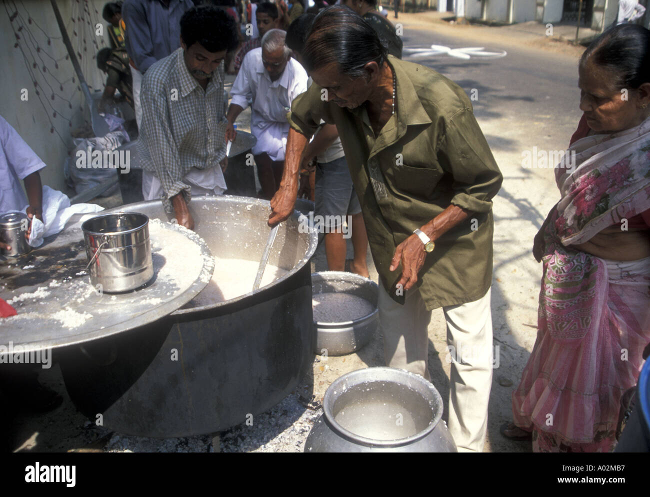 Volunteers cooking a cauldron of rice given free to worshippers at a ...