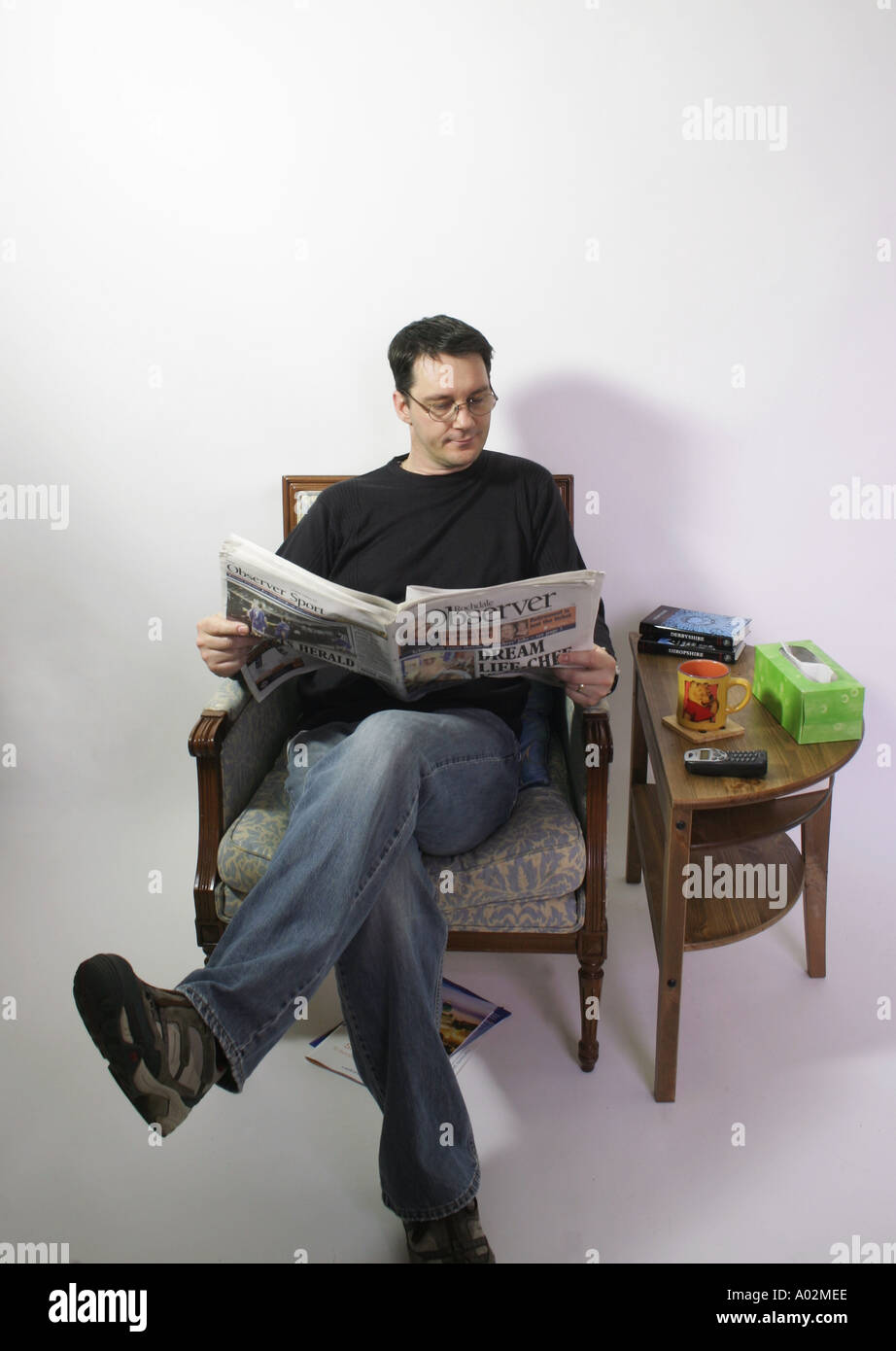 Man sitting down at home reading newspaper and relaxing Stock Photo - Alamy