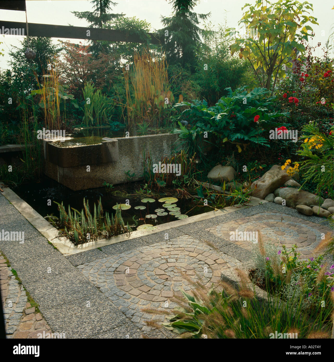 Water falling from large trough into rectangular pond below, with ...