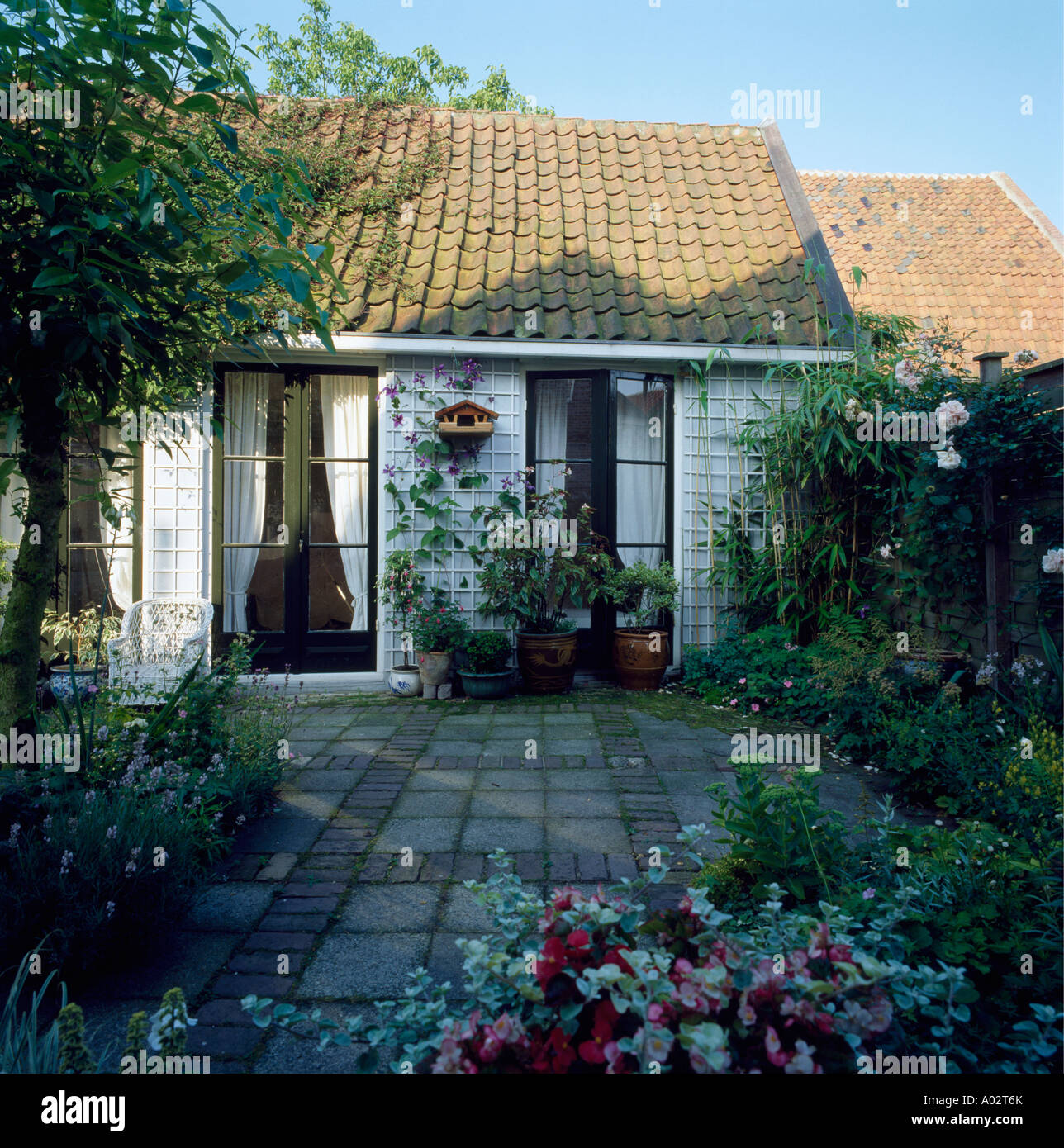 Paving and flower borders in paved courtyard front of small white ...