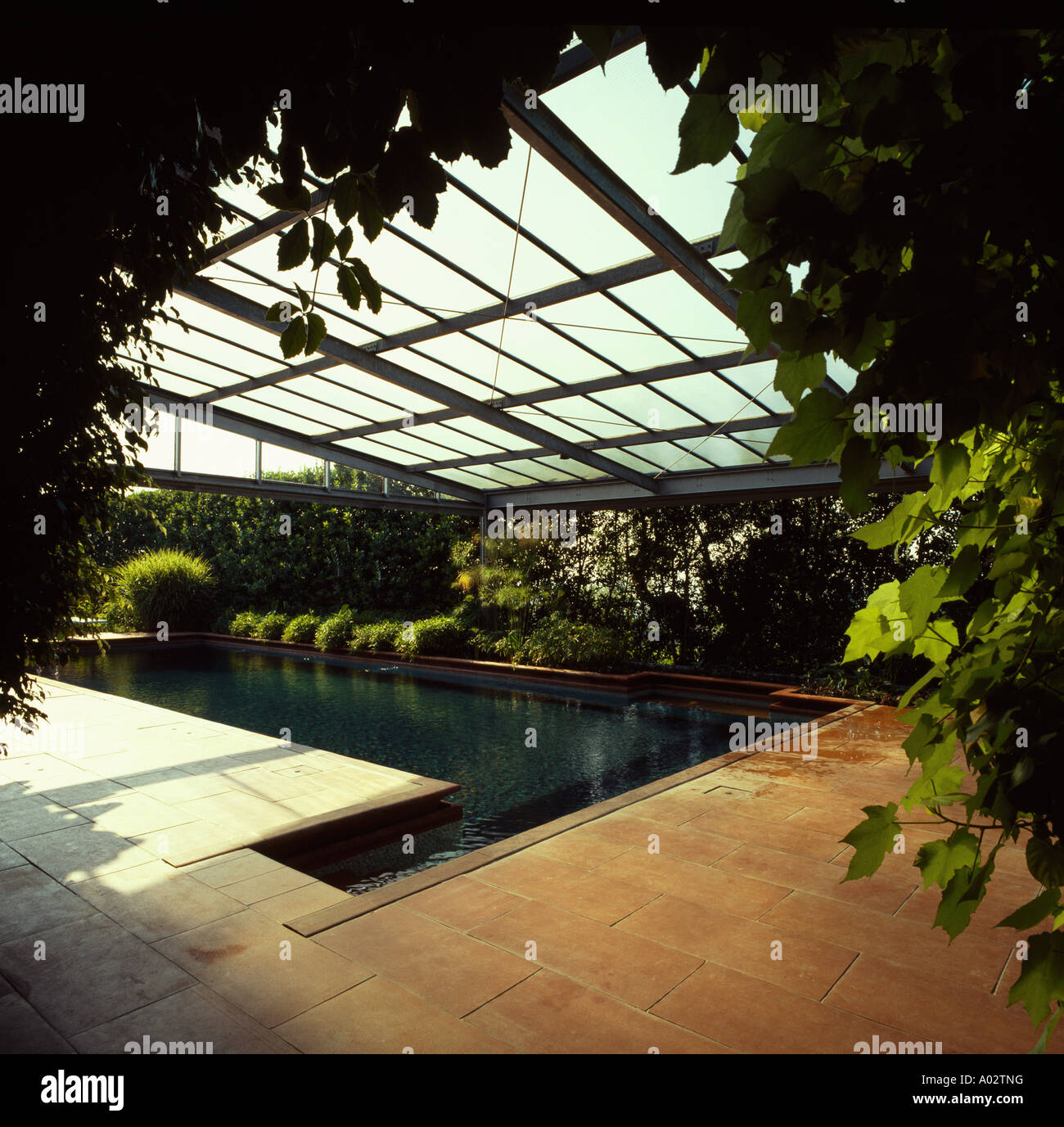 Retractable glass roof above indoor swimming pool with terracotta tiled ...