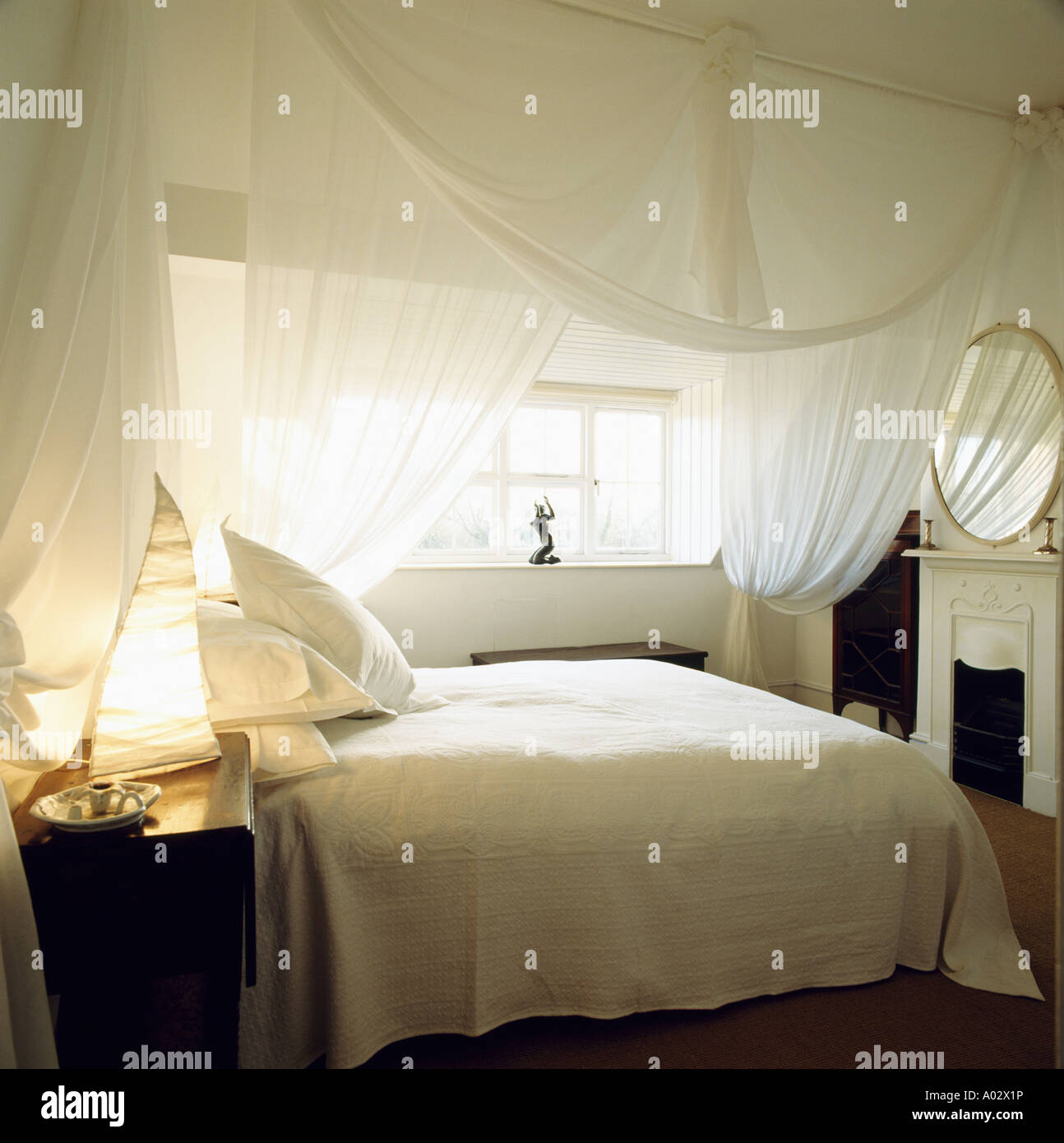 Draped muslin above bed in white townhouse bedroom Stock Photo - Alamy