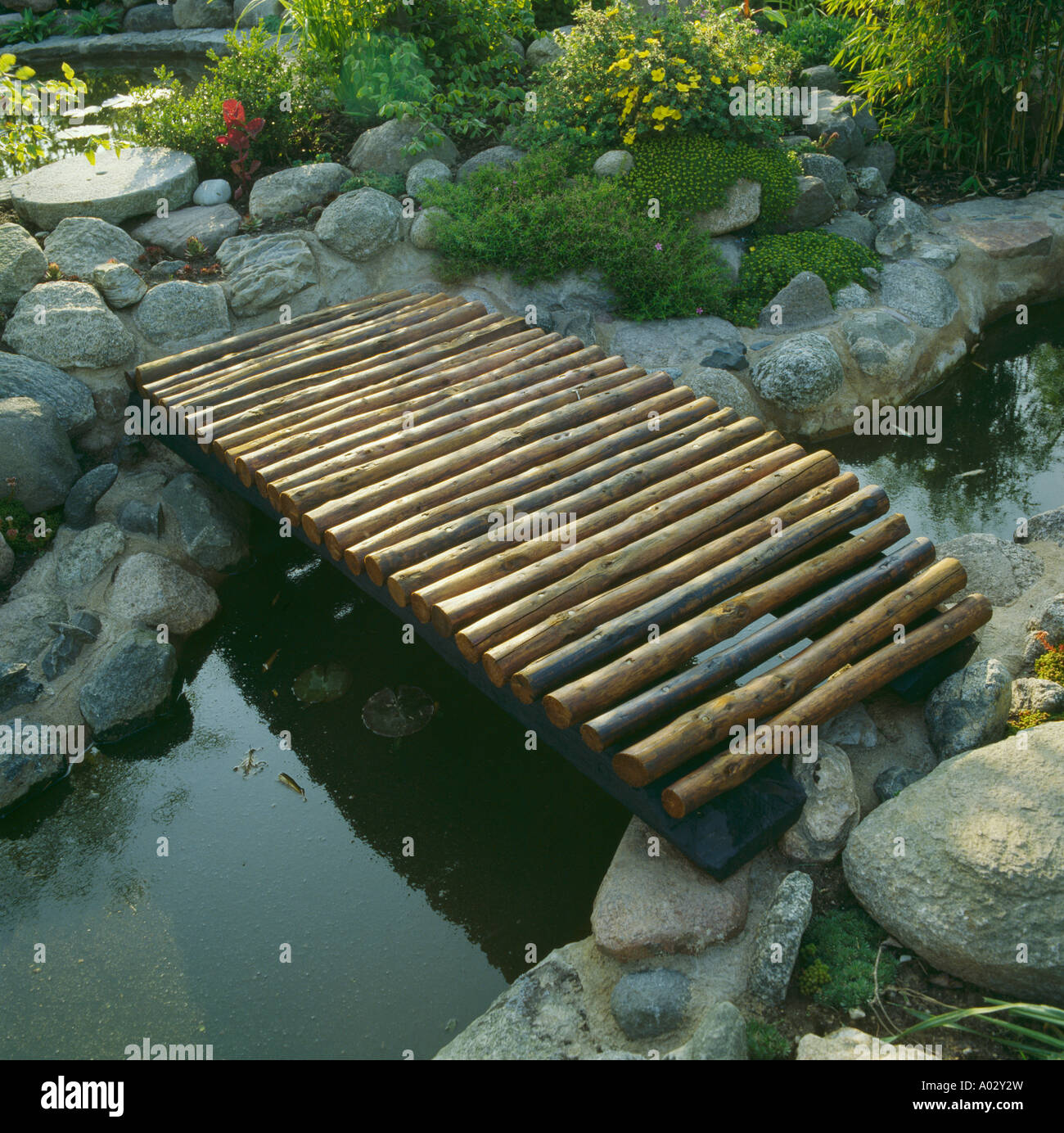 Wooden log bridge over stream in country garden Stock Photo - Alamy