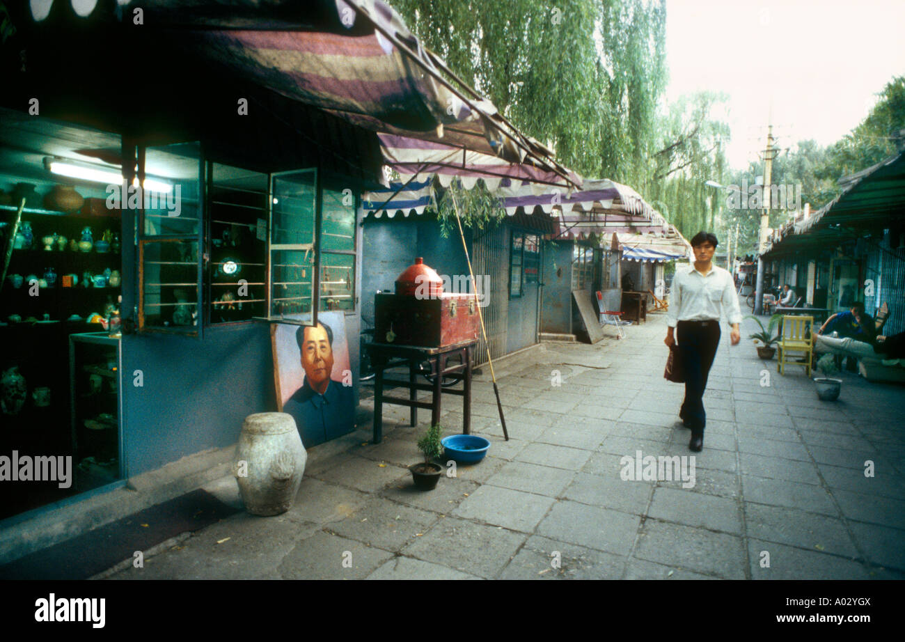 Man walking down the back streets of old Beijing city past shops ...
