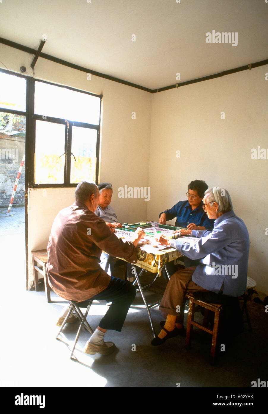 Chinese friends sitting around table playing chinese game in the old ...