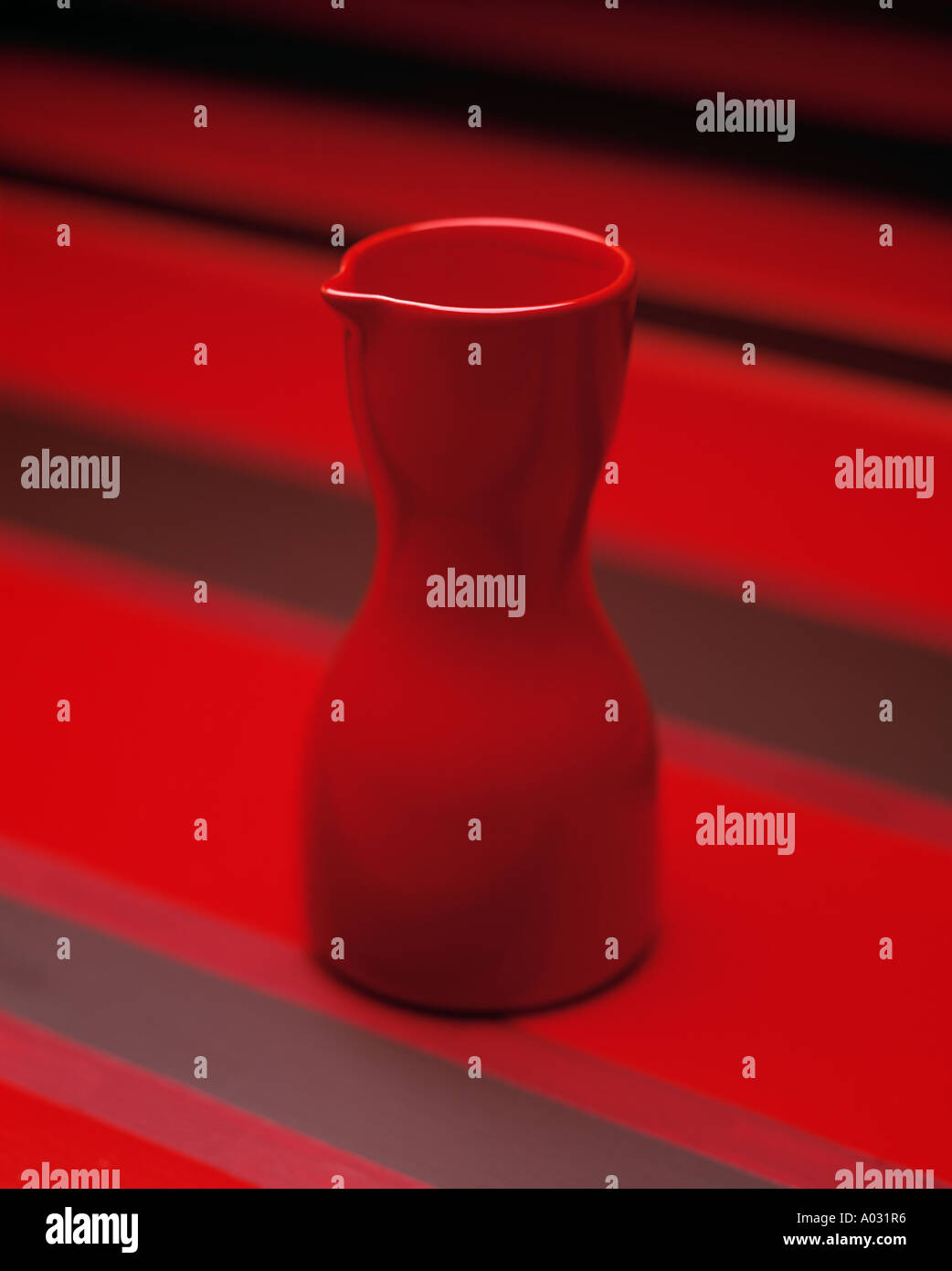 Still Life of red jug on stripey background Stock Photo - Alamy