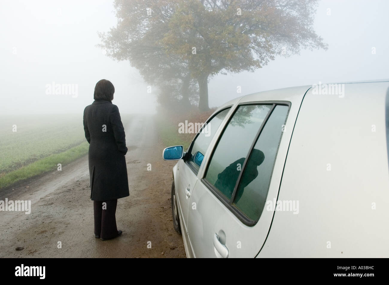 Atmospheric foggy scene of woman stranded next to broken down car Stock ...