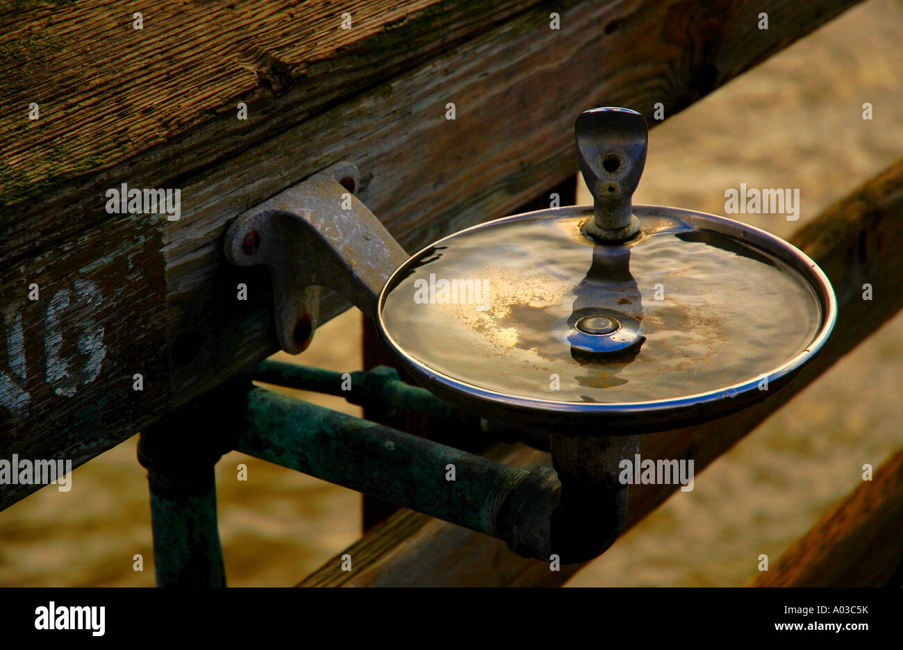 Rough drinking water fountain mounted on wood railing in afternoon ...