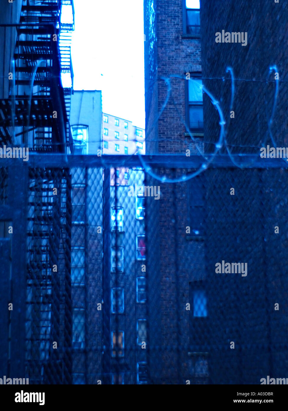 Coils of barbed wire atop a wrought iron fence in front of an alleyway ...