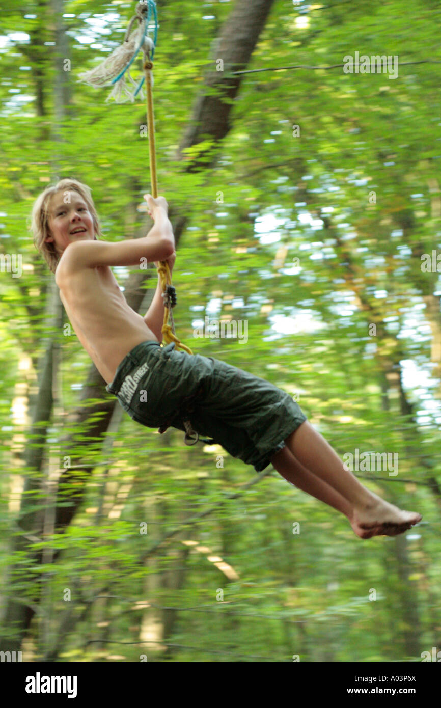 a young boy swinging on a rope in a forest Stock Photo - Alamy