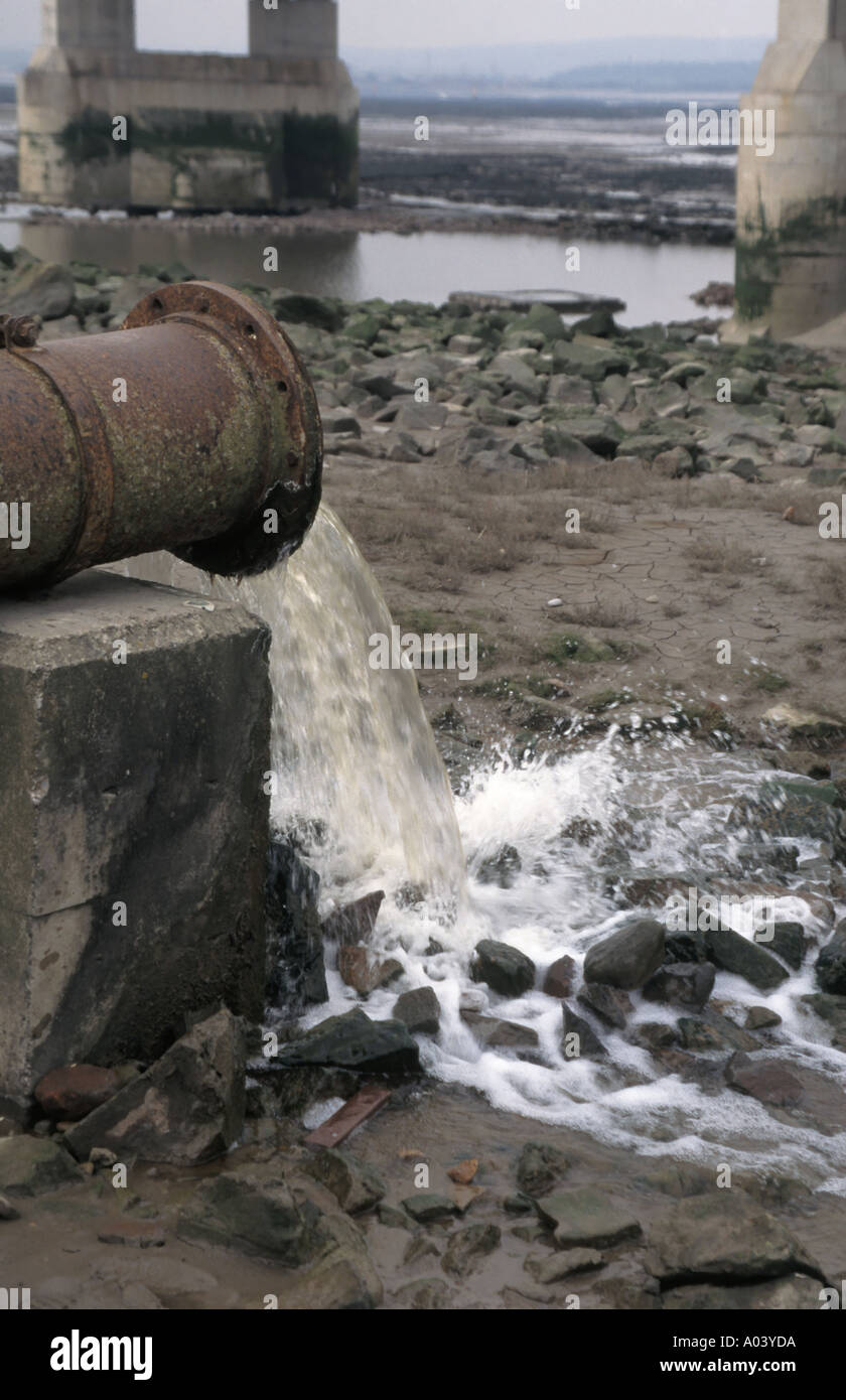 Close up iron pipe discharging water onto foreshore of muddy River ...