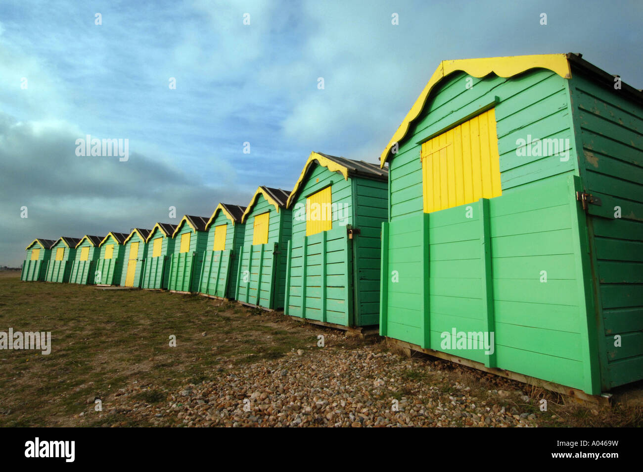 A row of freshly painted traditional seaside beach huts on the shore at ...