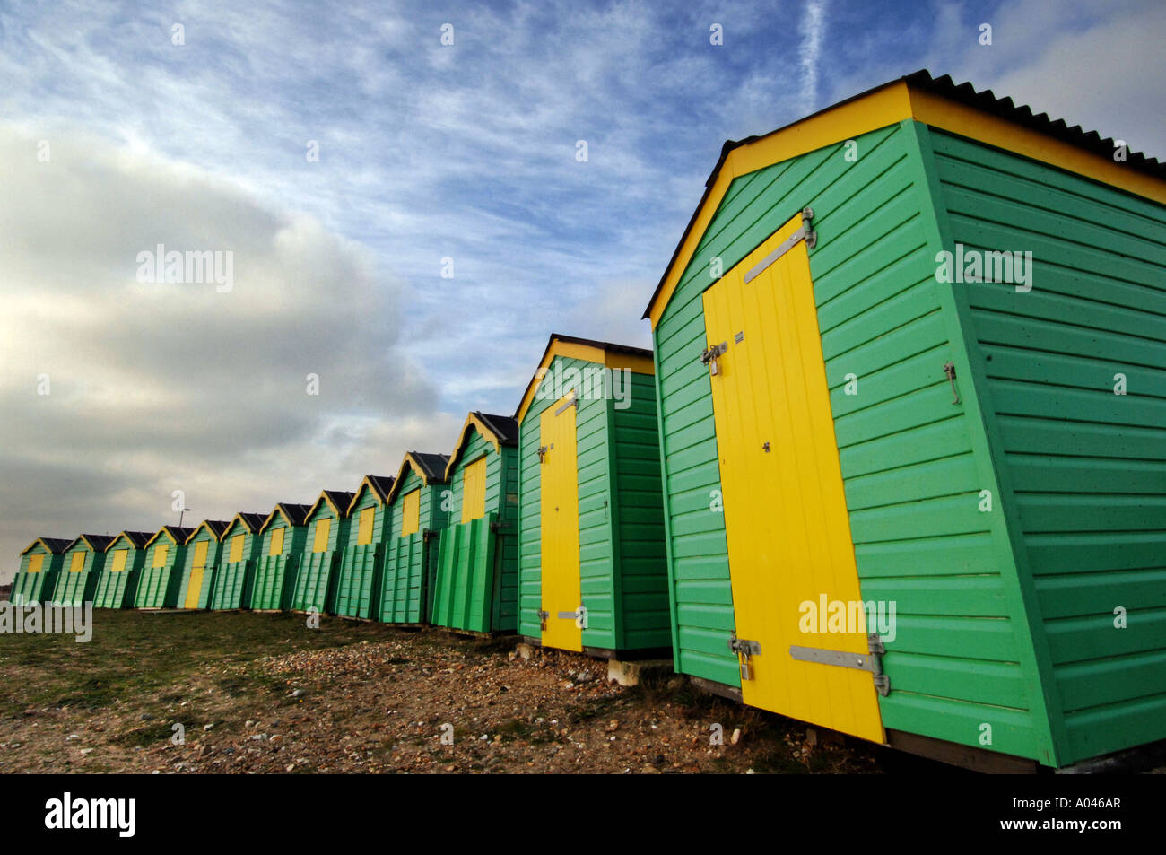 A row of freshly painted traditional seaside beach huts on the shore at ...