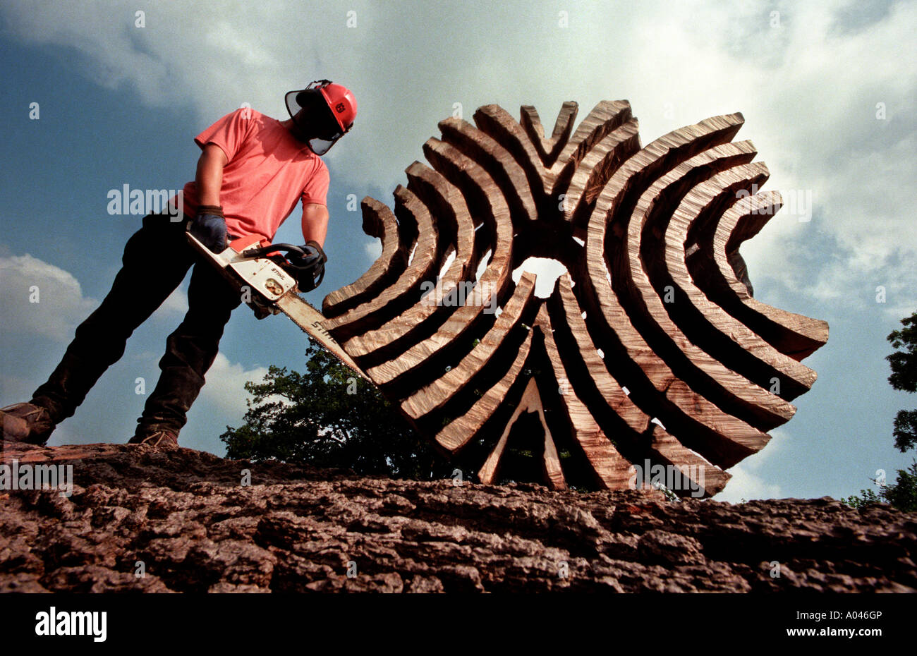Recycled wood being turned into a sculpture by man in hard hat with ...