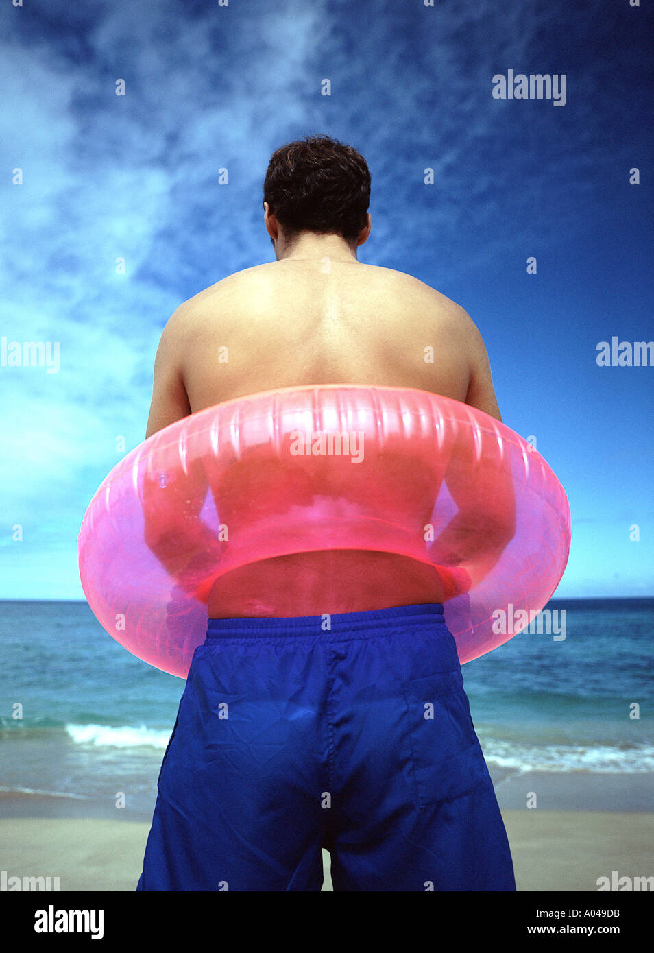Young man wearing pink inflatable rubber ring aroung his waist looking ...