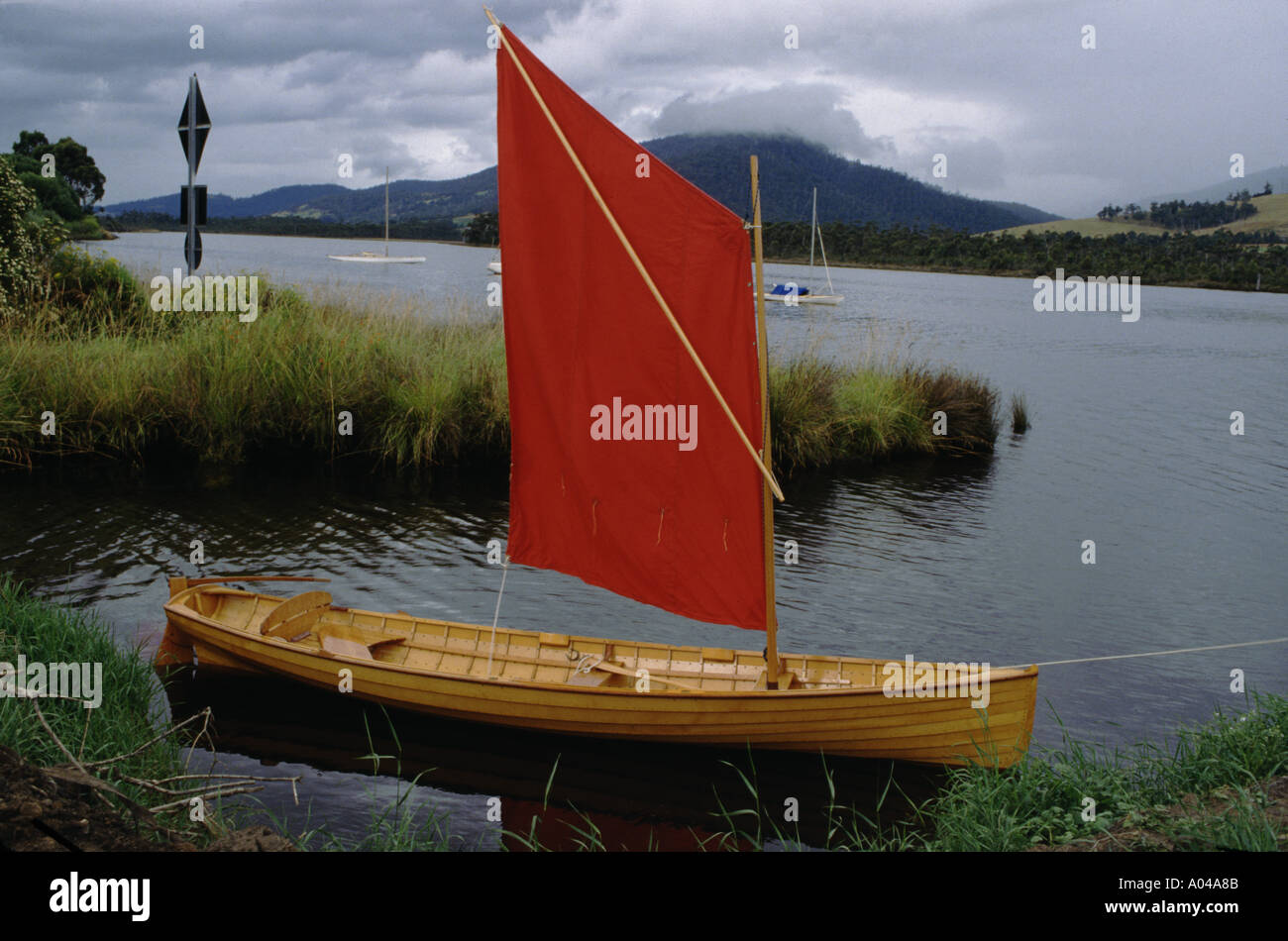 Wooden boat 17ft Whitehall rowing skiff with red lug-rigged sail on the ...