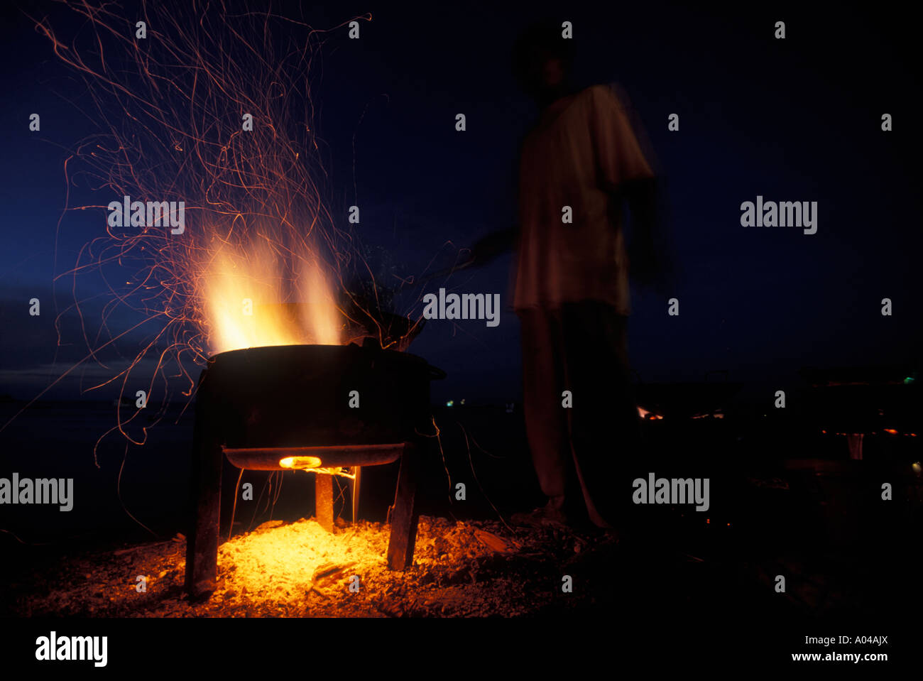 Africa Tanzania Zanzibar Stone Town Vendor stands by charcoal brazier ...
