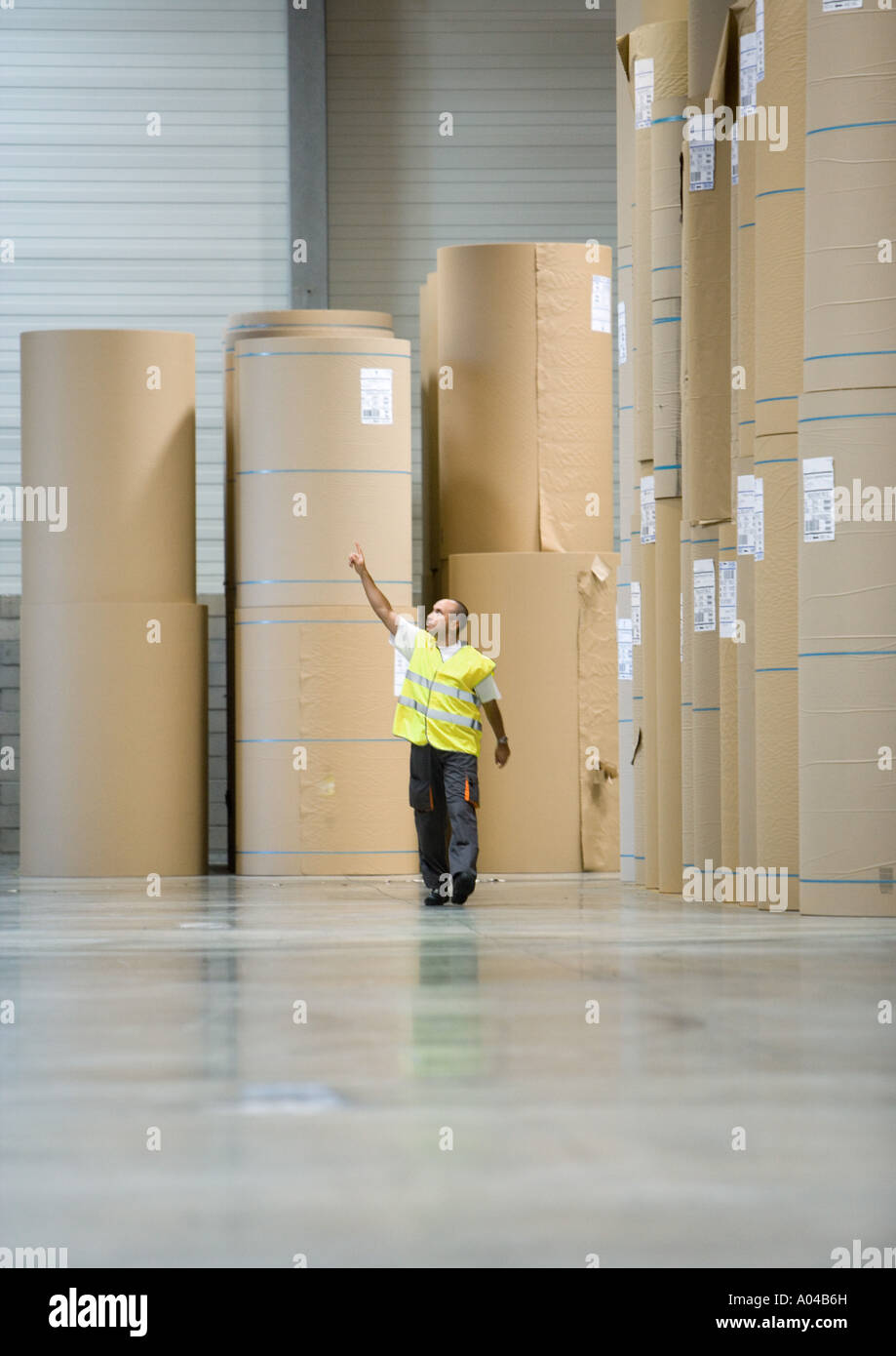 Factory worker standing next to rolls of paper, pointing Stock Photo ...