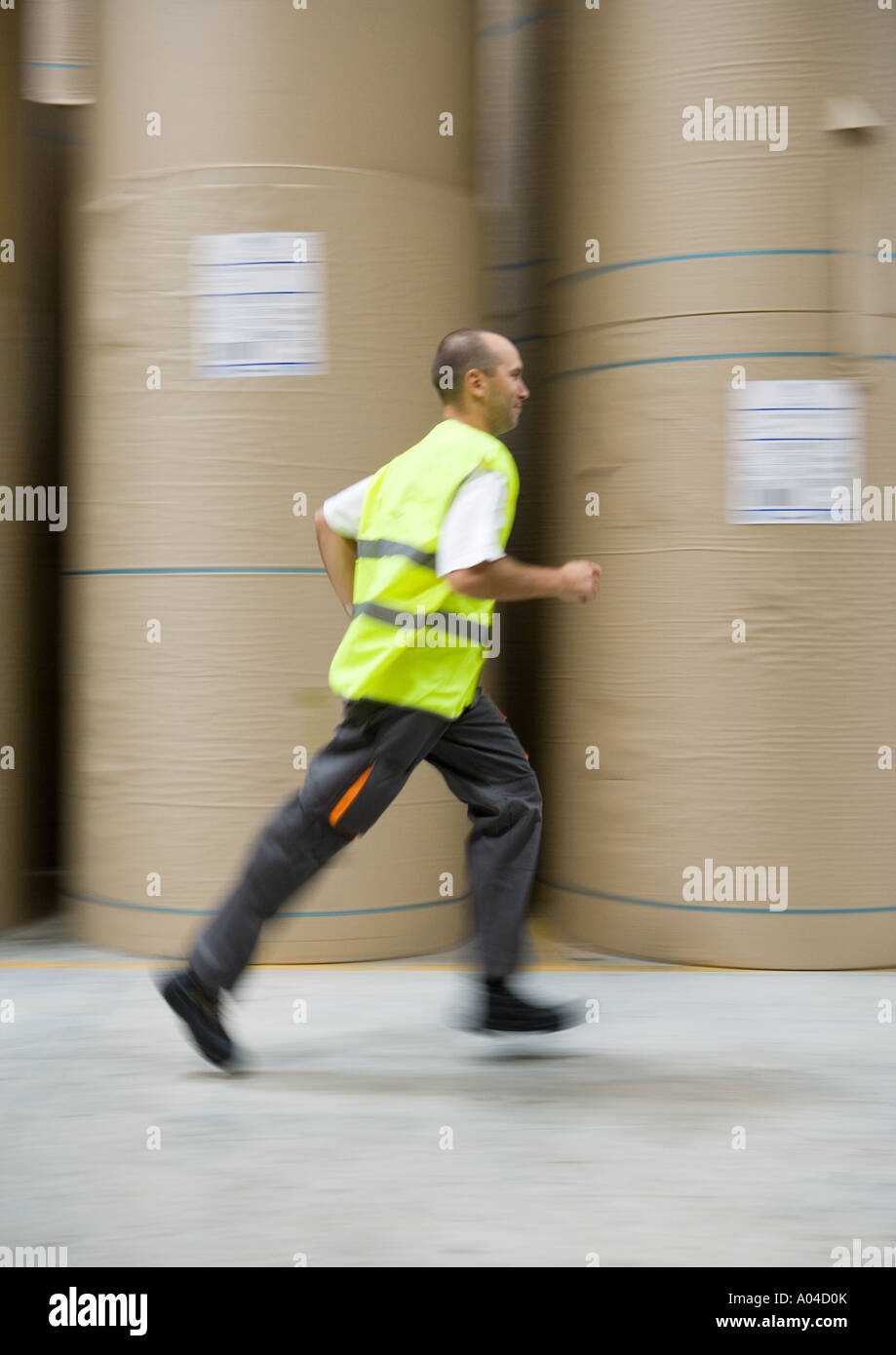 Man running past rolls of paper in warehouse Stock Photo - Alamy