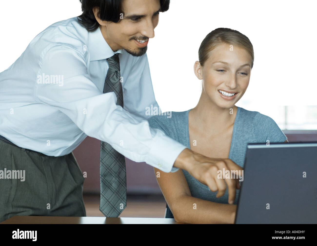 Businessman helping female colleague with computer Stock Photo - Alamy