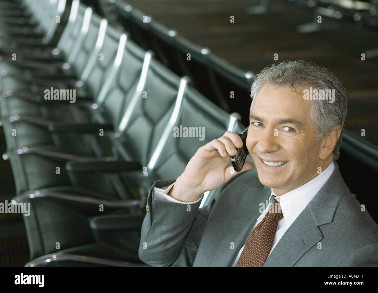 Businessman using cell phone in airport lounge Stock Photo - Alamy