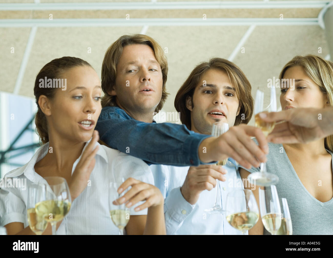 Man reaching over friends' shoulders for glass of champagne Stock Photo ...
