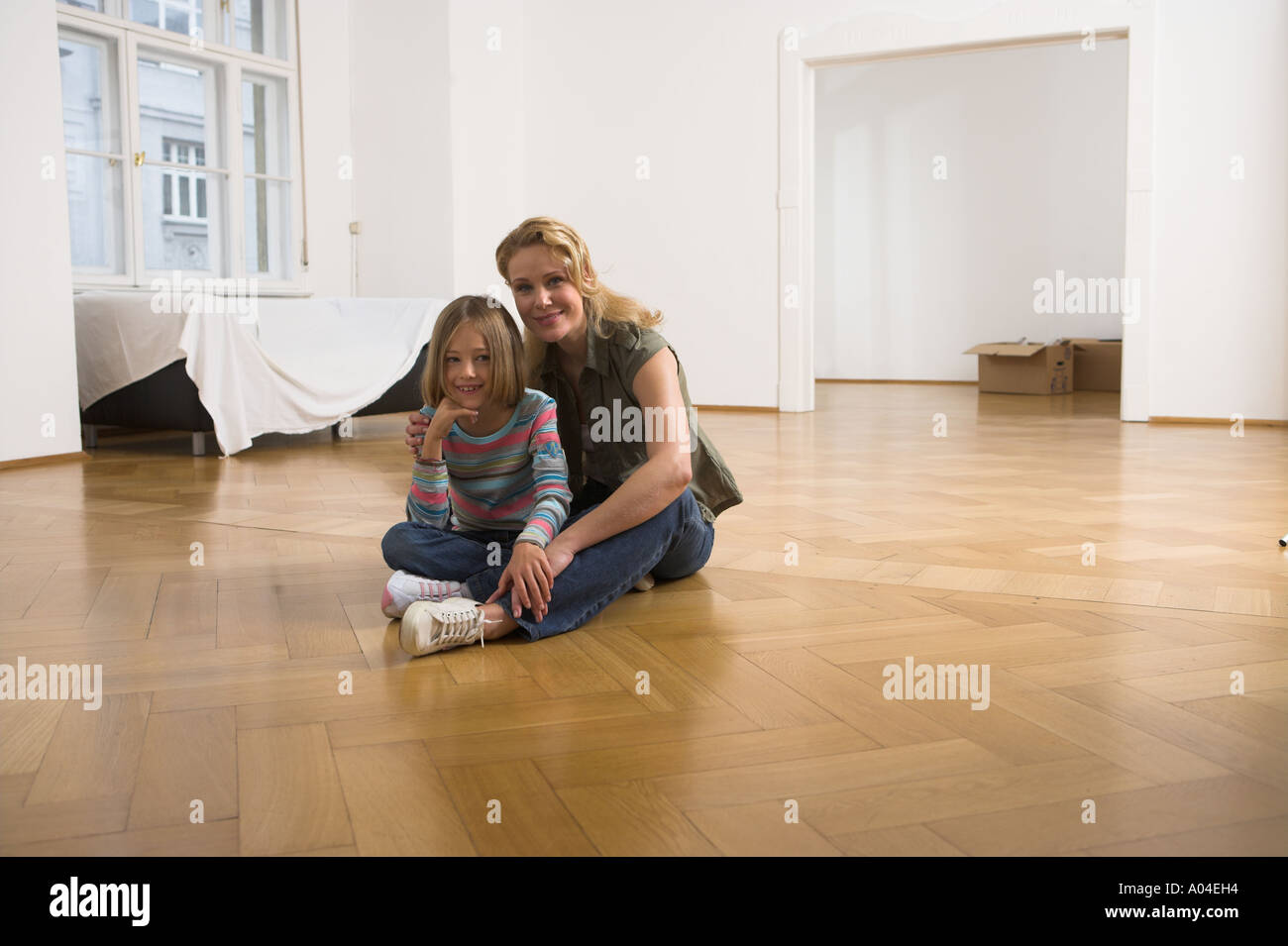 portrait of mother and daughter in an empty room after moving into new ...