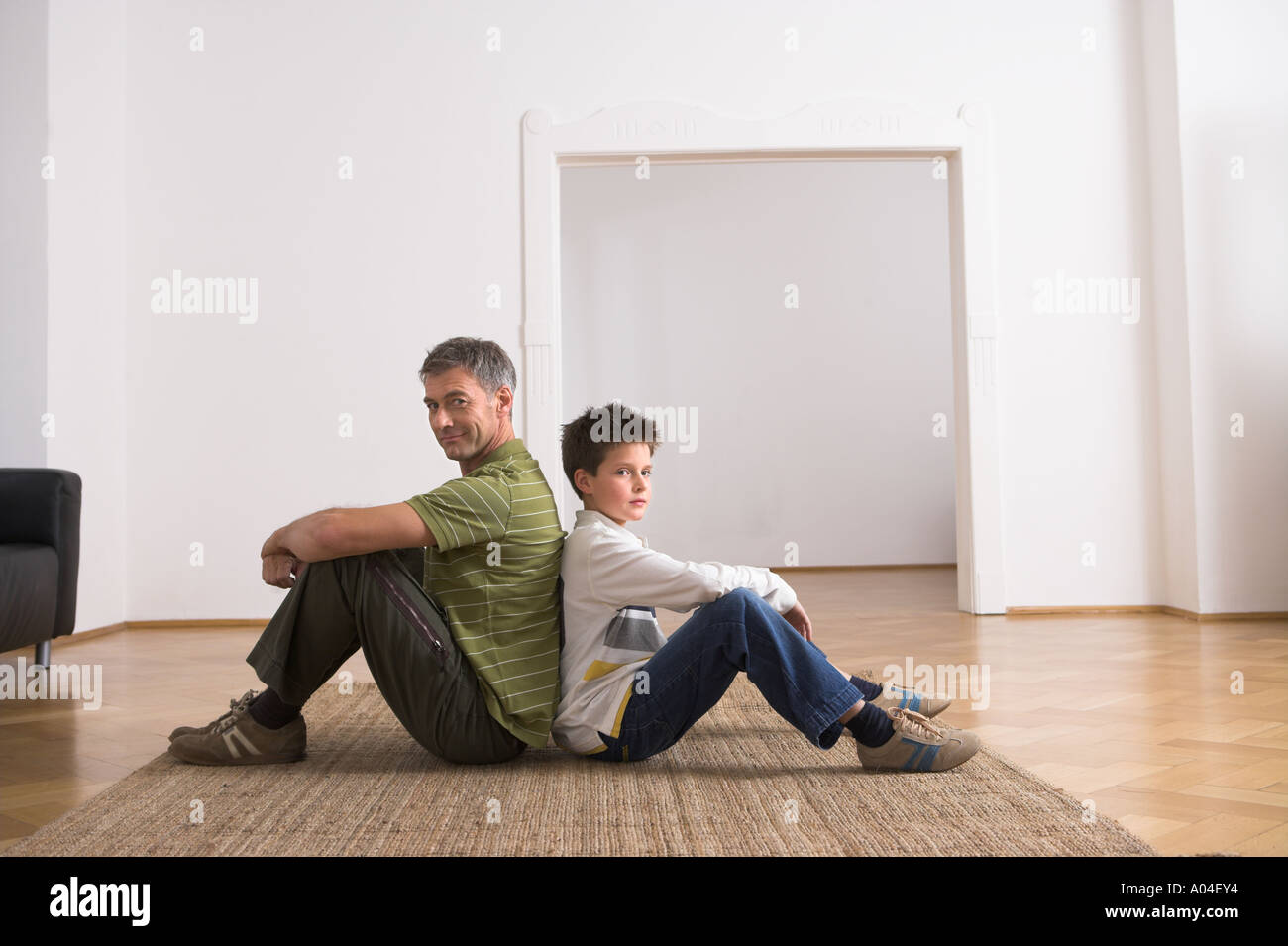 portrait of father and son sitting back to back Stock Photo - Alamy