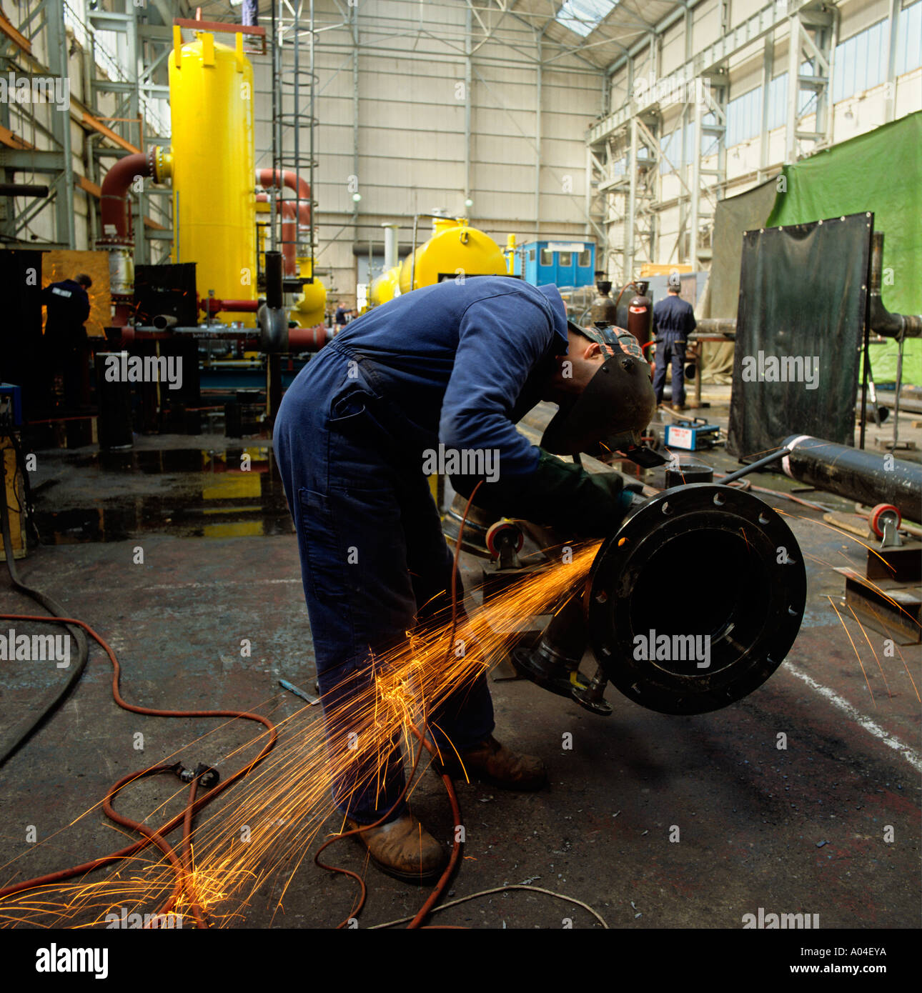 Industry man angle grinding pipework Stock Photo - Alamy