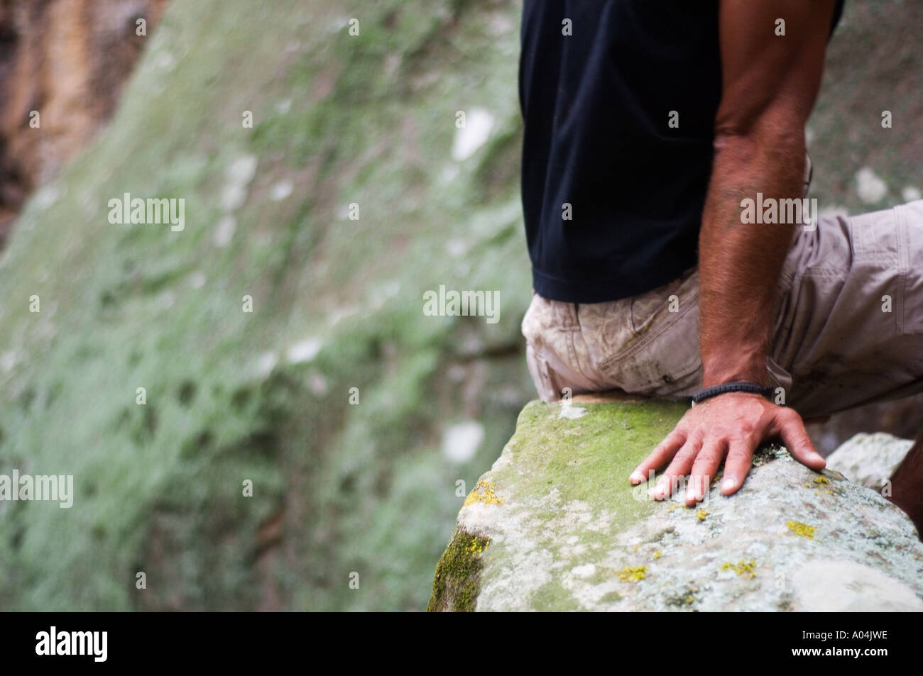 Cropped and rear view image of a man sitting against rock partly ...