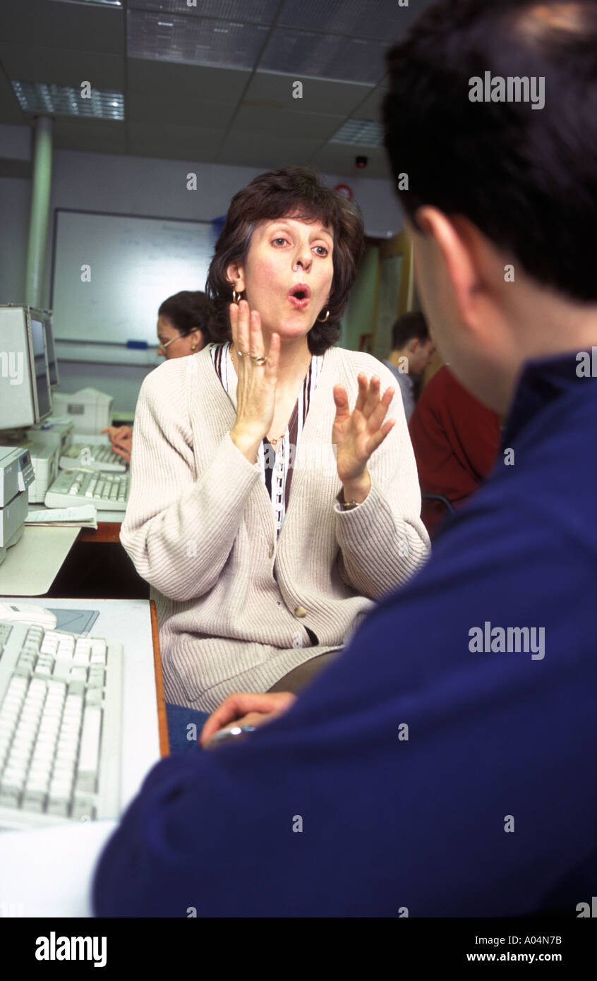 Deaf teacher working with hearing impaired adult students on computers ...