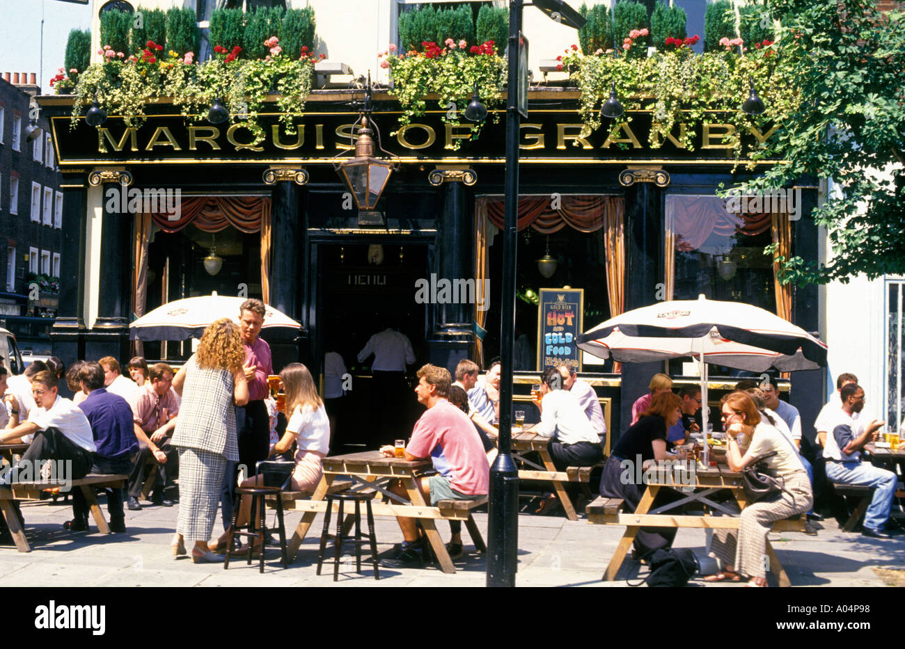 people sitting outside a pub drinking and socialising London Stock ...