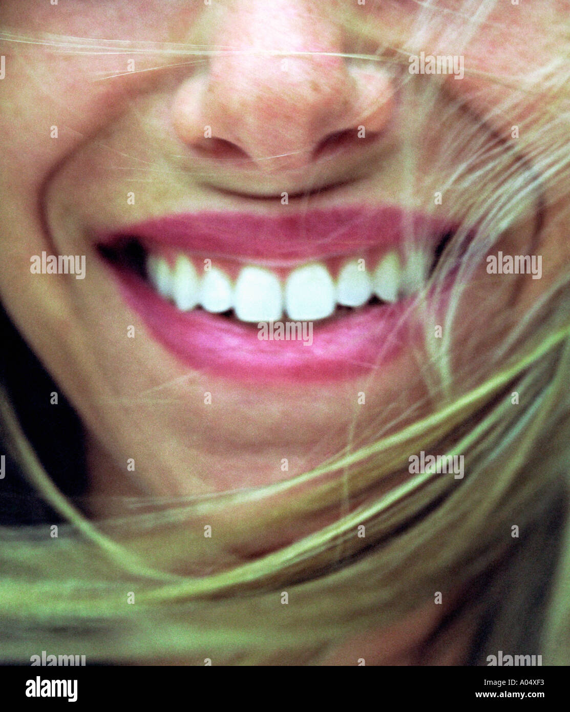 A close-up of a woman smiling with the wind blowing and showing her ...